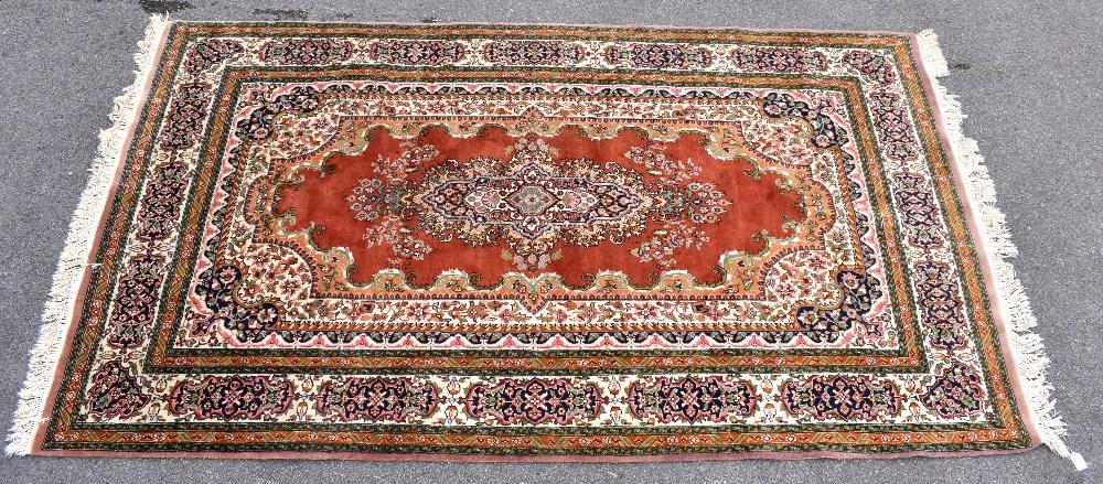 A large Middle Eastern style rug with floral motif, on a red orange and ...