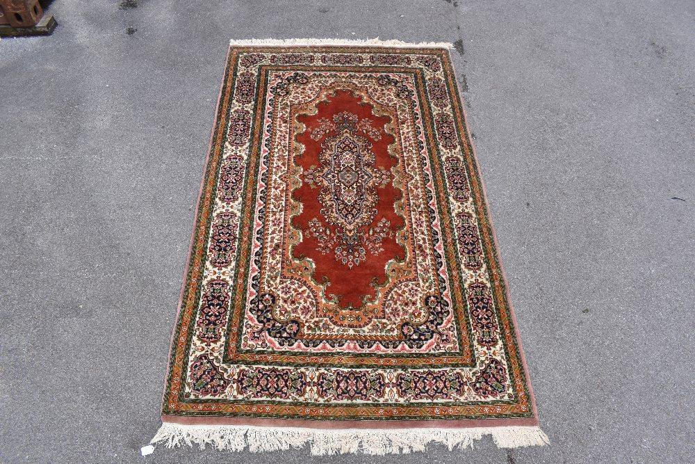 A large Middle Eastern style rug with floral motif, on a red orange and ...