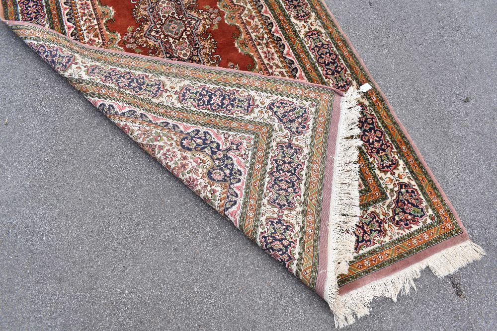 A large Middle Eastern style rug with floral motif, on a red orange and ...