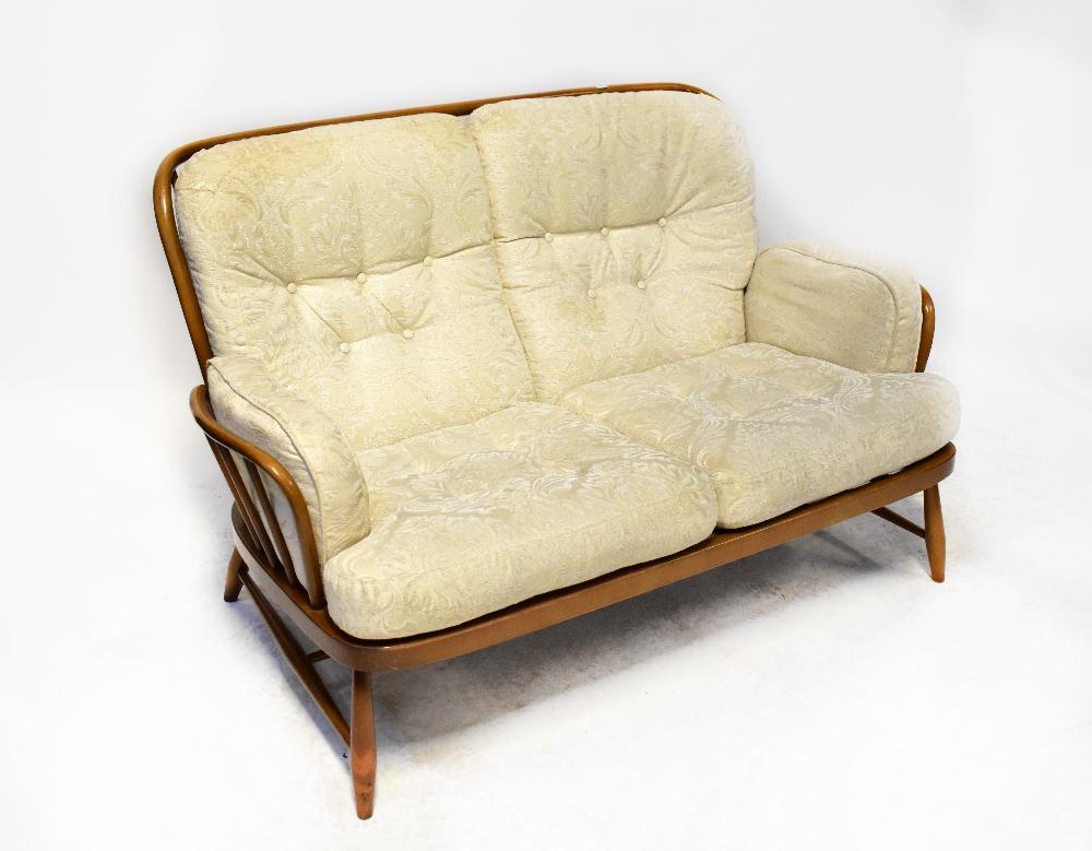 ERCOL; a Jubilee two-seater stick back settee, raised on turned cross ...