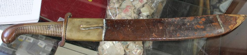 A serrated edged sabre, the steel blade with brass handle, the guard ...