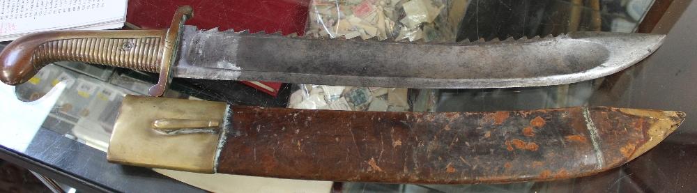 A serrated edged sabre, the steel blade with brass handle, the guard ...